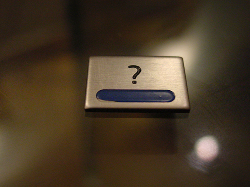 A photograph of a machine type button that has a question mark on it