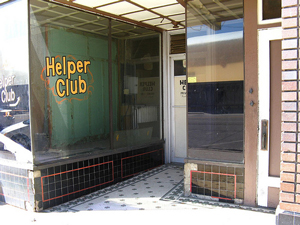 Photo of a downtown store window that reads “Helper Club”